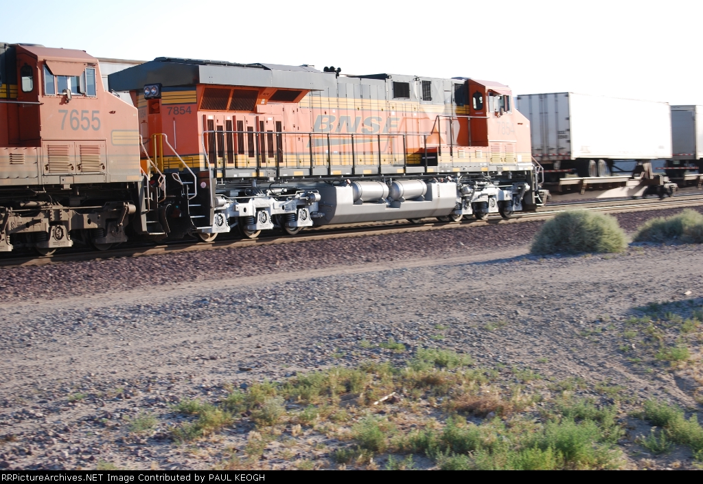 BNSF 7854 and BNSF 7655 pass me by as the rising sun reflects of their BNSF Swoosh Logo.
